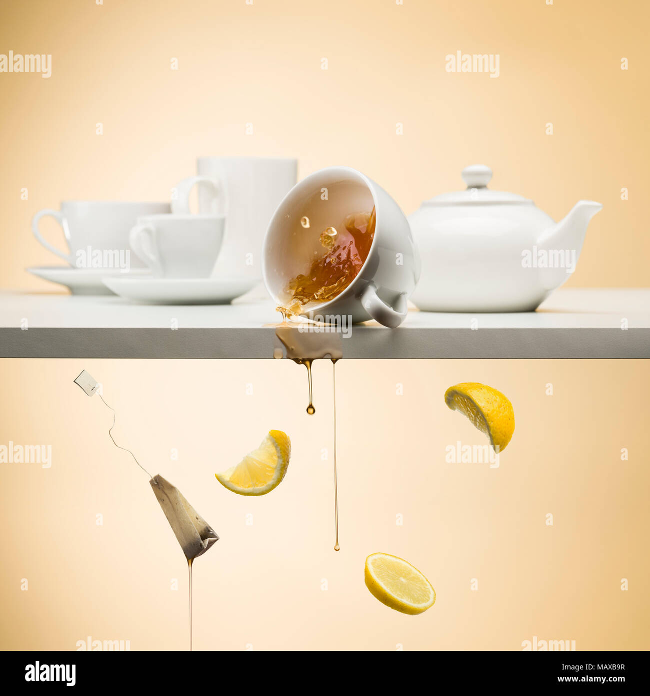 falling cup of tea dripping from white table with teabag and lemon ...