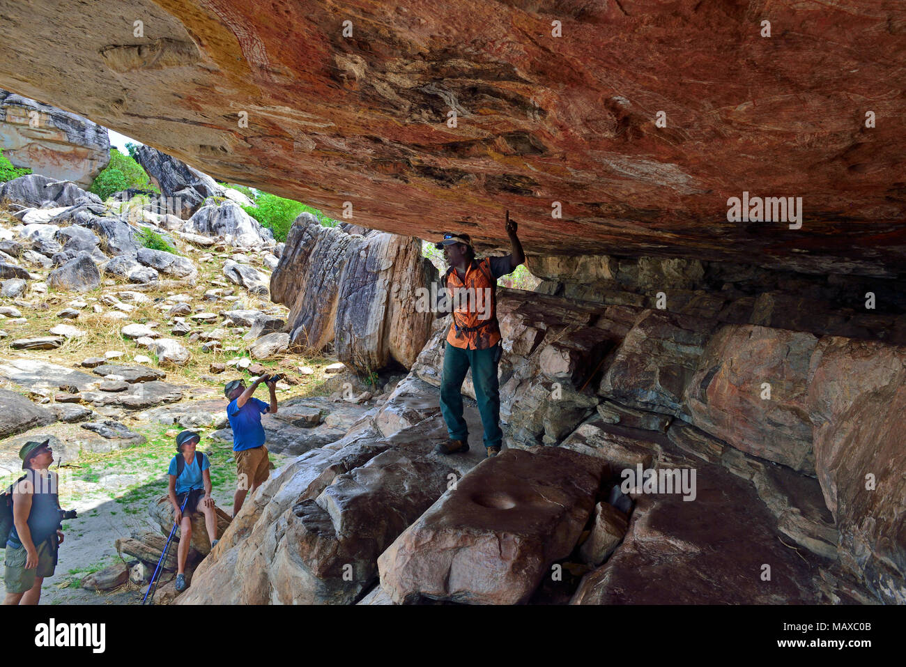 Aboriginal tour guide points out rock art to tourists on Anjalak Hill ...