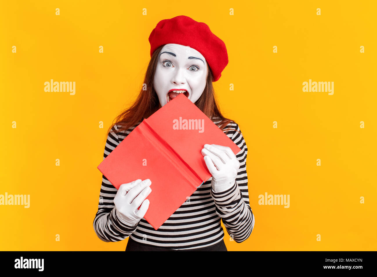 Portrait of crazy mime woman eating red book. Emotions and feelings ...