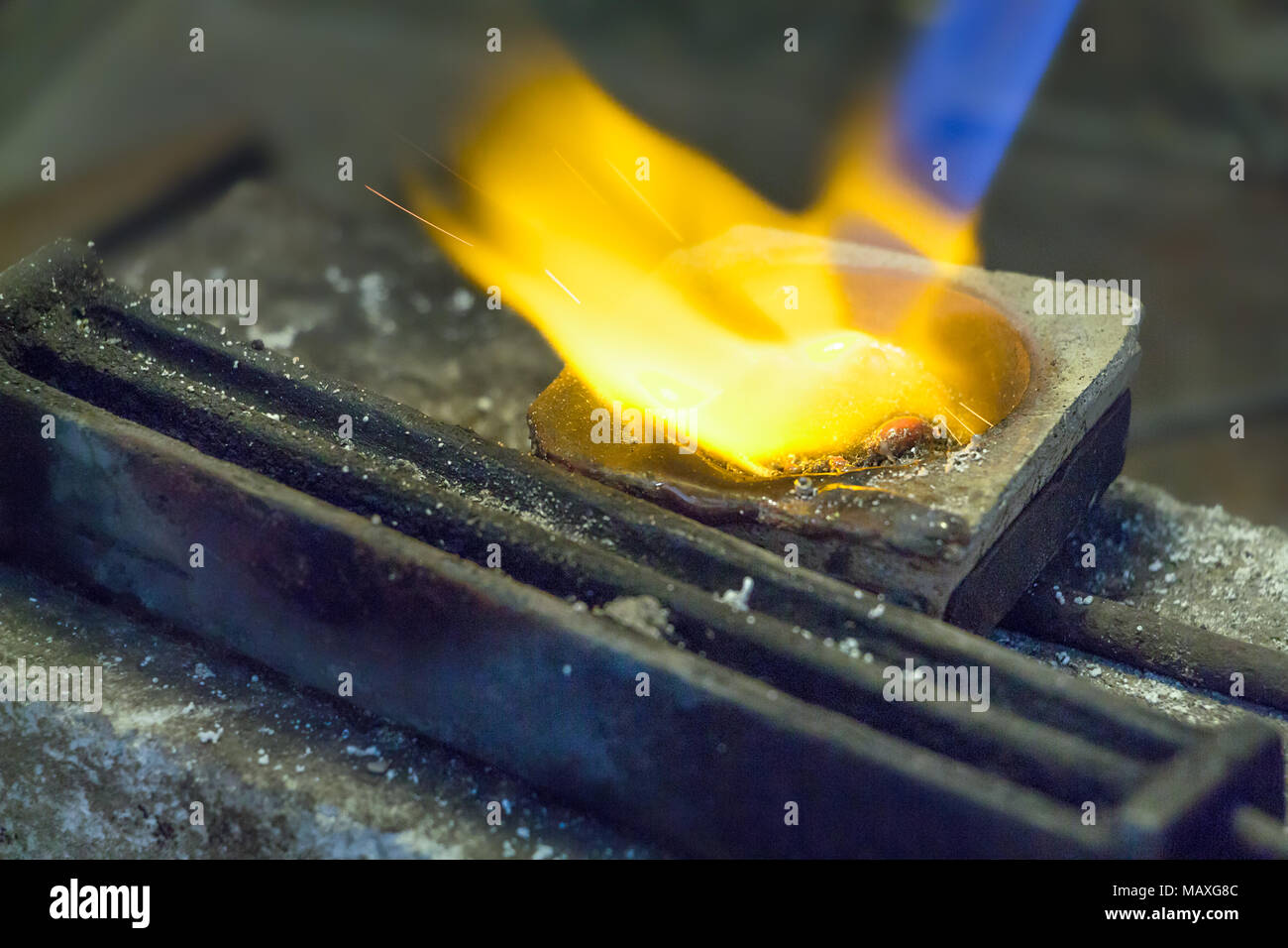 Jeweler melting silver on a ceramic melting pot with a gas torch and a ...