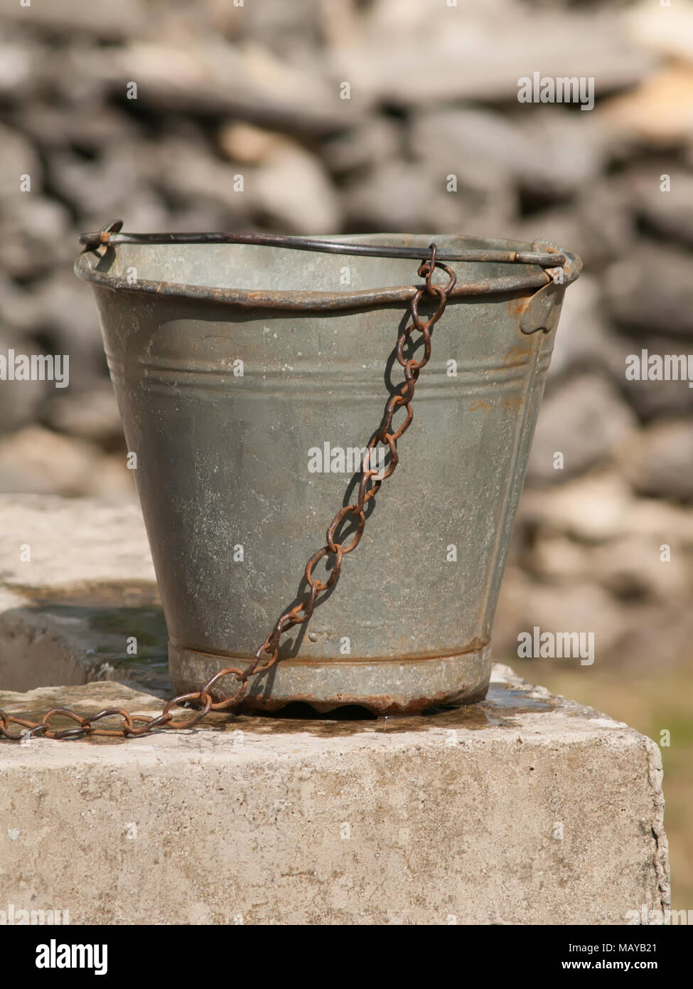 Retro pottery. Old rusty water bucket on well with chain and blured ...