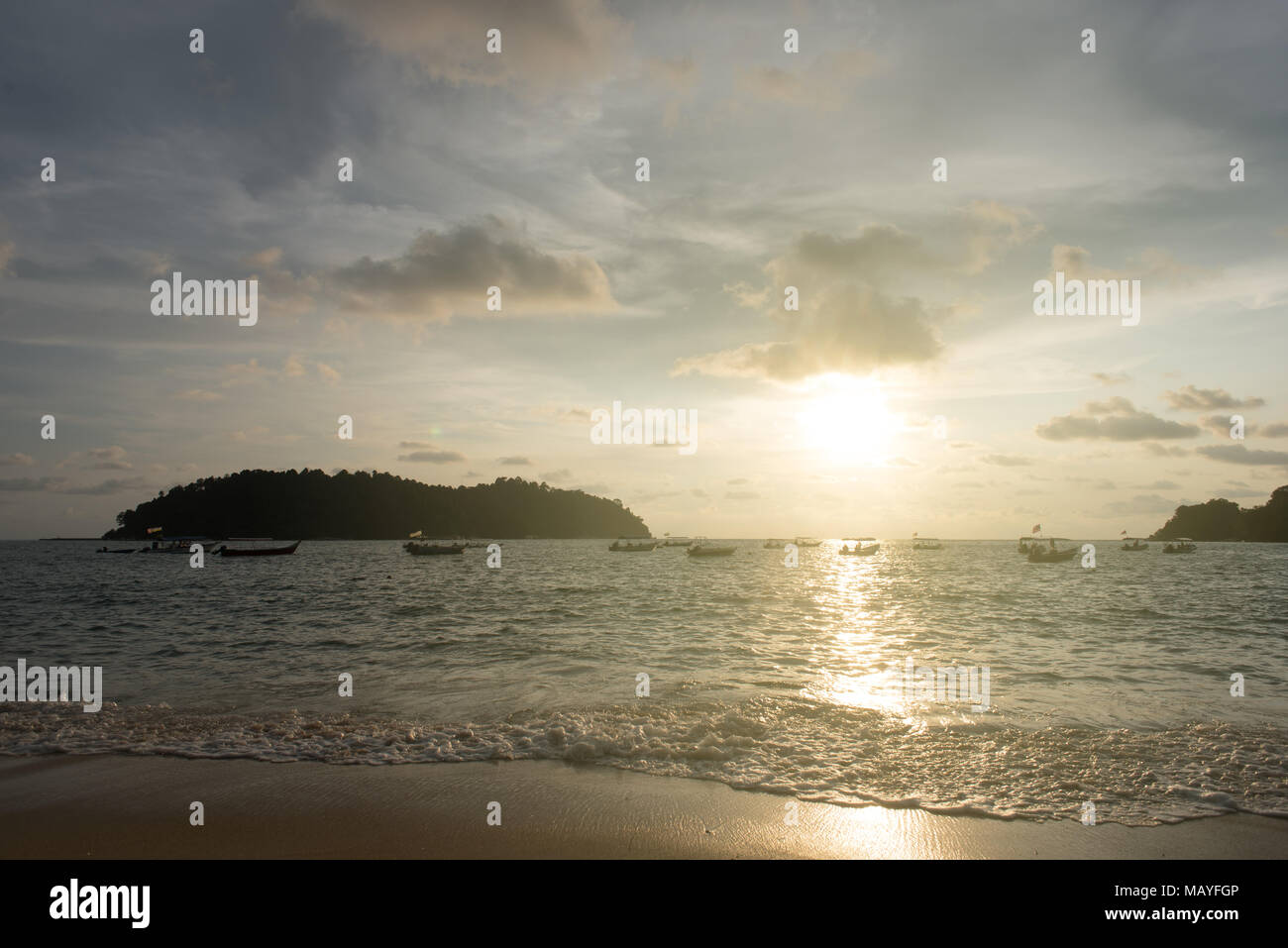 view of a sunset sky and silhouette of floating boats and small island ...