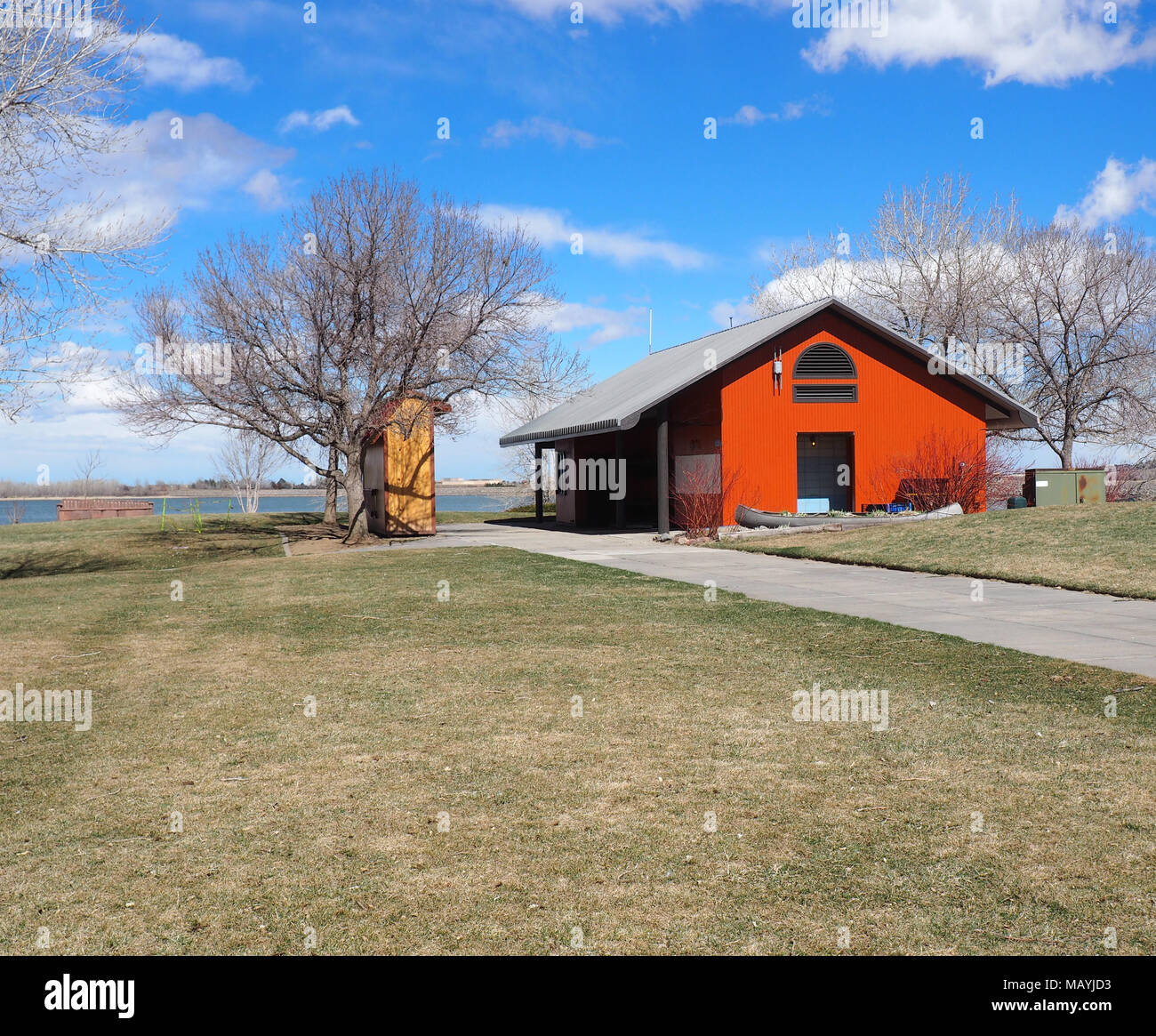 Red pole barn by a lake and grass area Stock Photo - Alamy