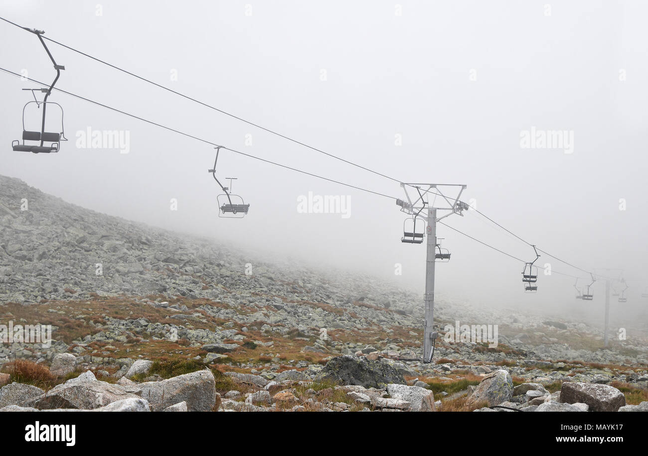 Mountain cableway chairlift in clouds and fog, high angle side view ...