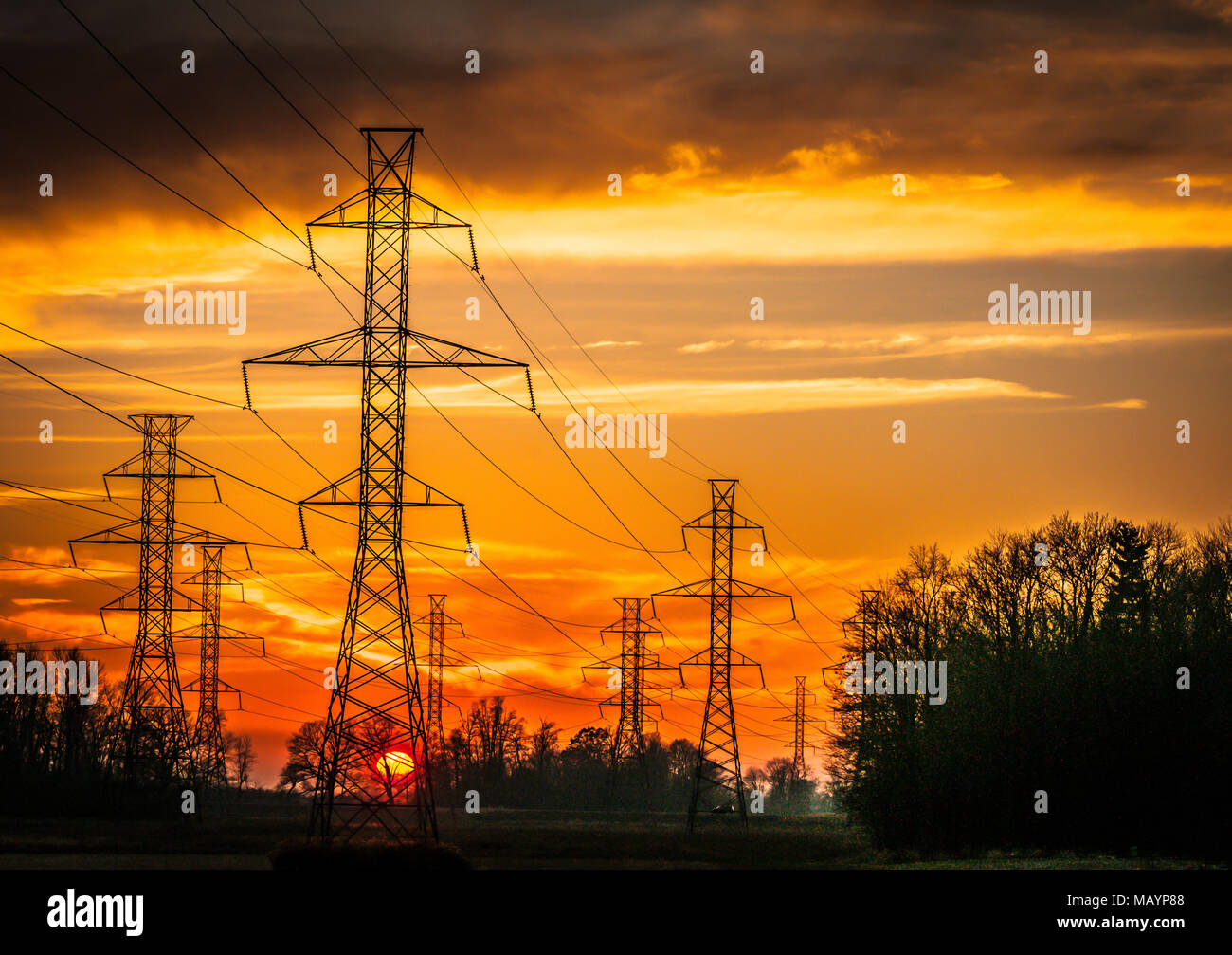 Silhouette of a power grid against a dramatic and colourful sunset sky ...