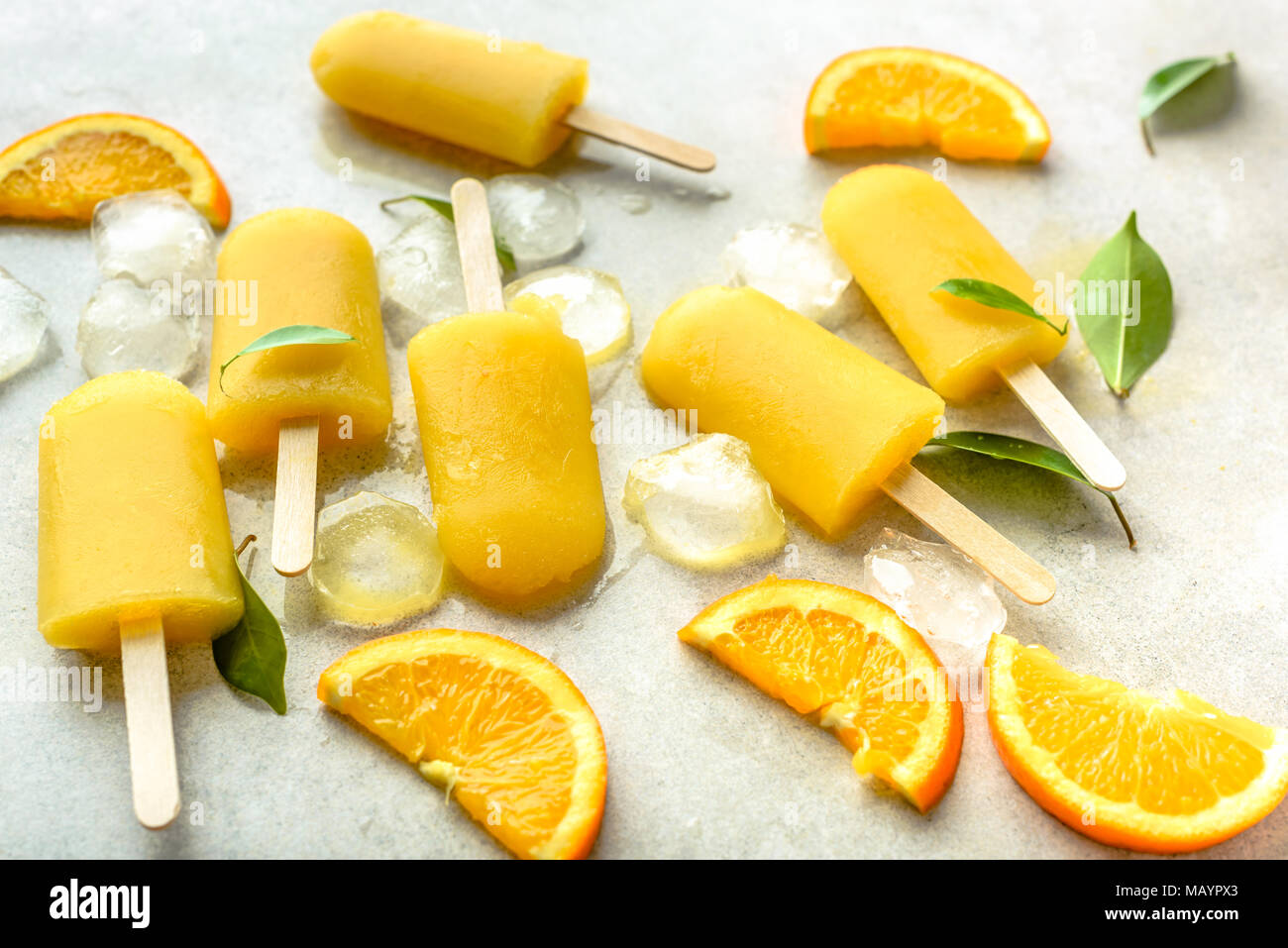 Orange popsicles with frozen juice and ice cubes, summer refreshing ...