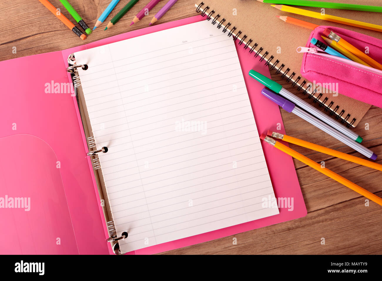 Busy student's desk with pink project folder surrounded by pens ...