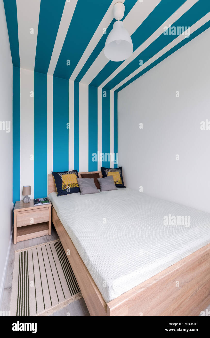 White and azure striped bedroom with big, wooden bed Stock Photo - Alamy