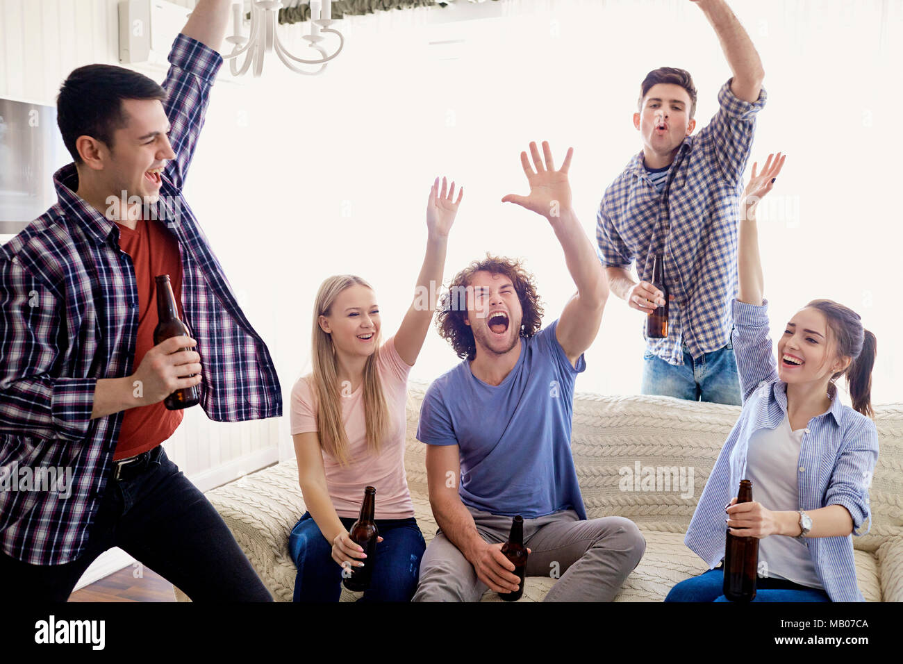 A group of friends at a party cheerfully raise their hands up Stock ...