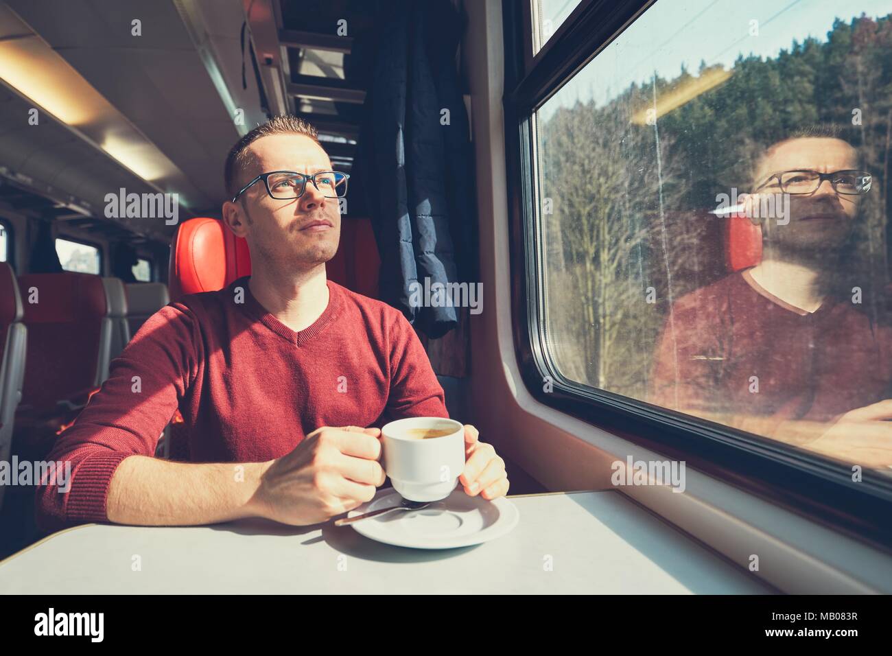 Rail transportation in sunny day. Pensive young man holding a cup of ...