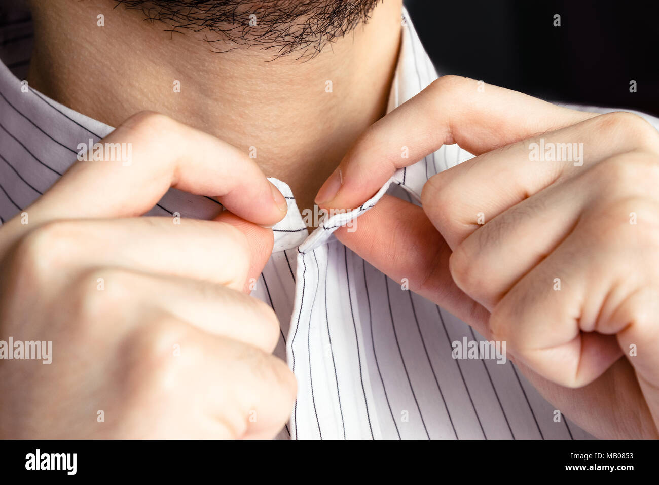 Young man fastens the collar of his white striped shirt Stock Photo - Alamy