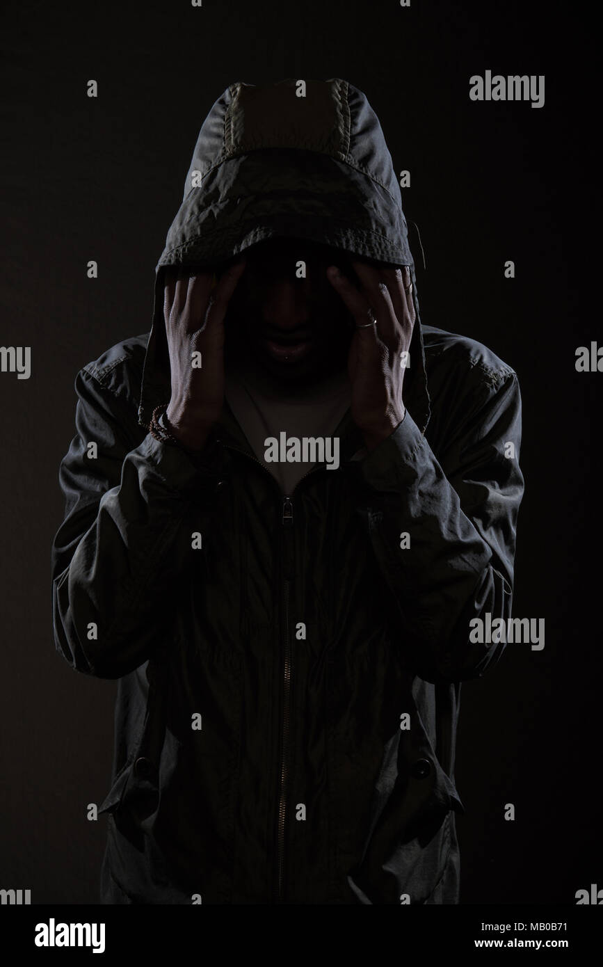 Hooded Male Holding Head in Hands Stock Photo - Alamy