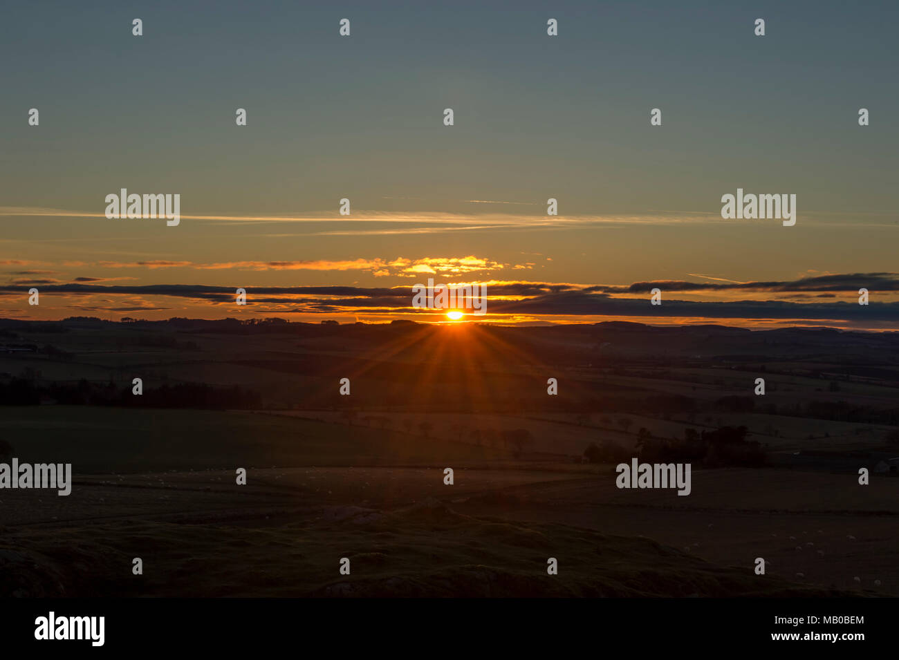 Sun rising over a green fields landscape Stock Photo - Alamy