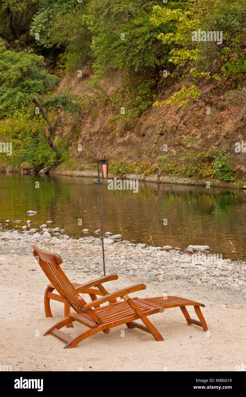 Two lounge reclining chairs by a river at a resort in California Stock ...