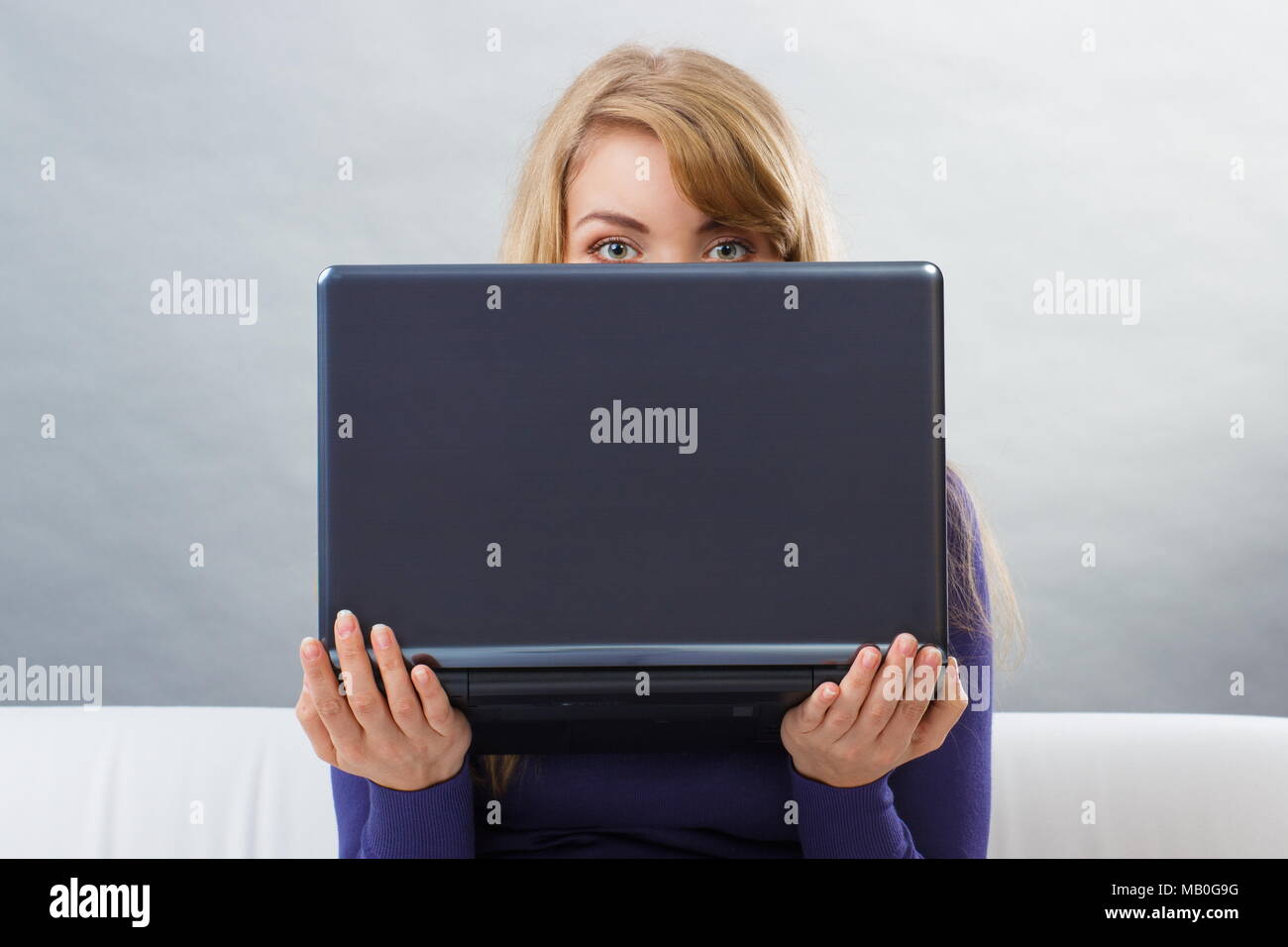 Woman hiding behind her laptop and looking out from behind computer ...