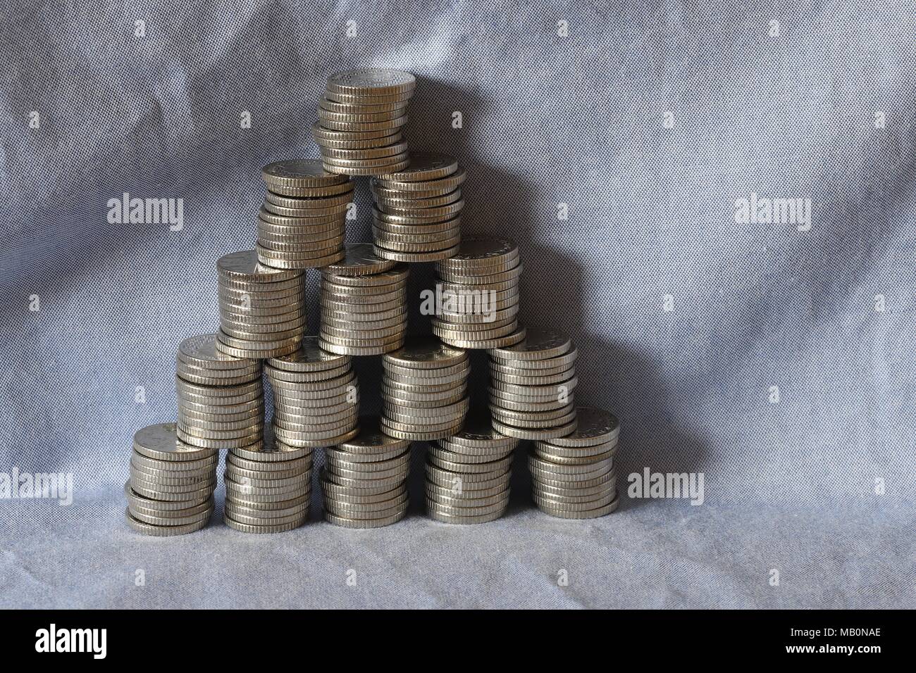 Pyramid stack of current (2018) British 5p coins against a light blue ...