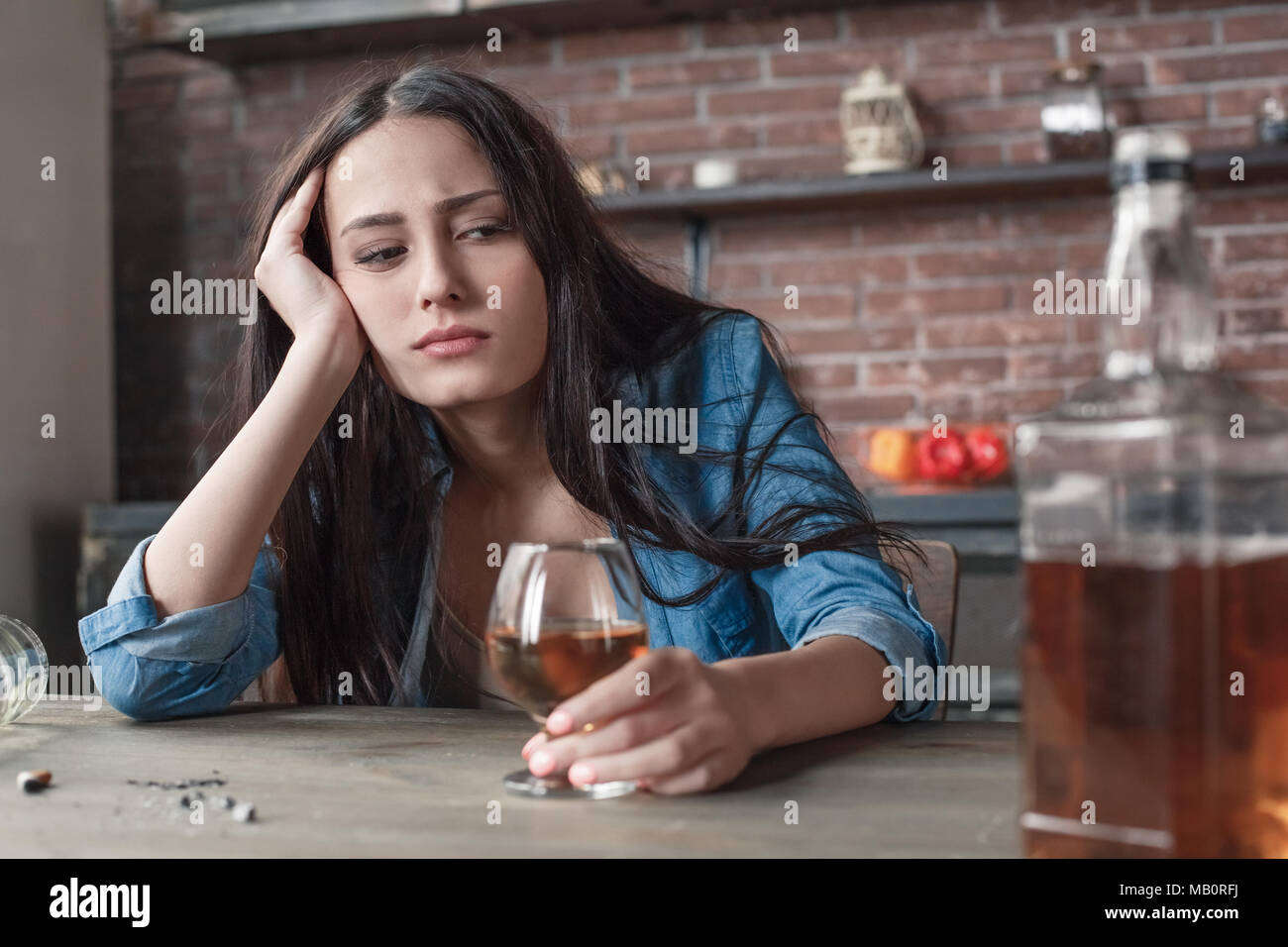 Young female alcoholic social problems sitting at table drinking ...