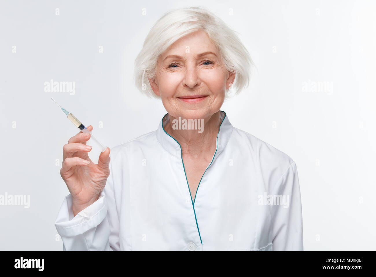 Aged female doctor studio isolated on white background holding syringe ...