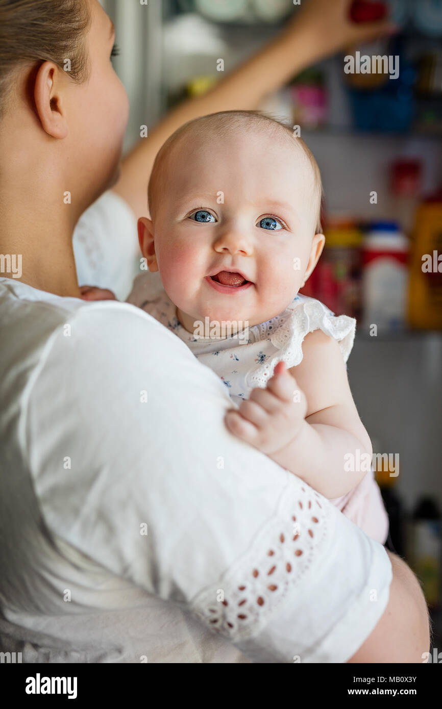 Smiling and cute baby girl with her caring mother working home Stock ...