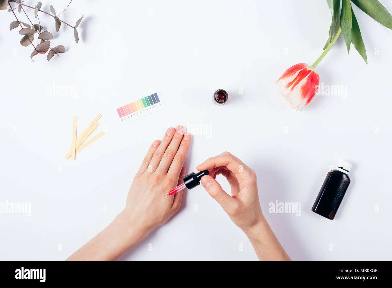 Top view of woman applying serum on her hand with pipette on white ...