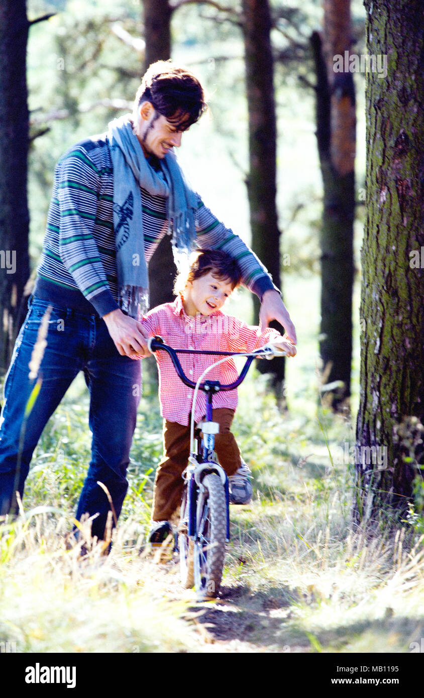 father learning his son to ride on bicycle outside, real happy f Stock ...