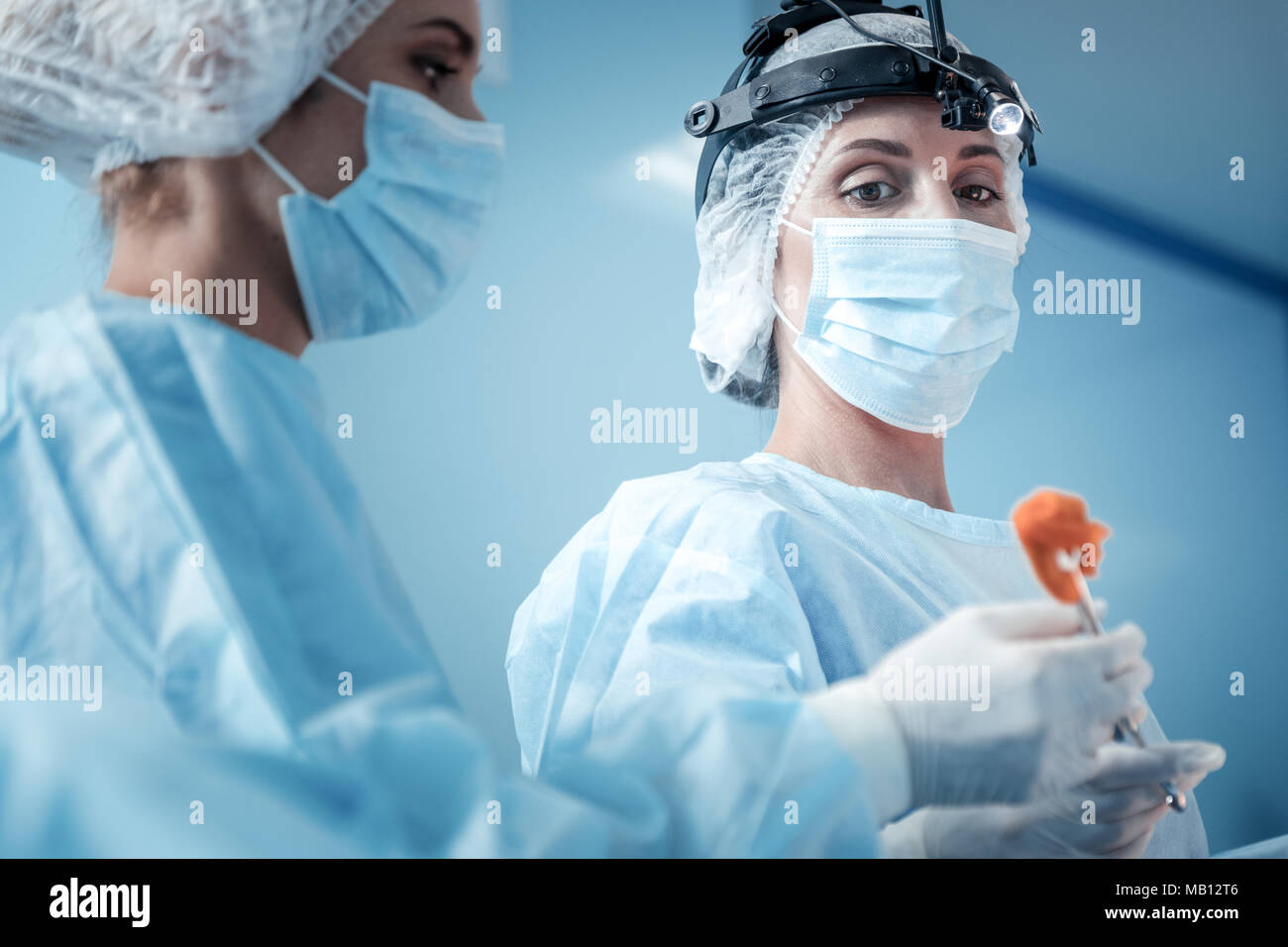 Nice smart surgeon taking scissors Stock Photo - Alamy