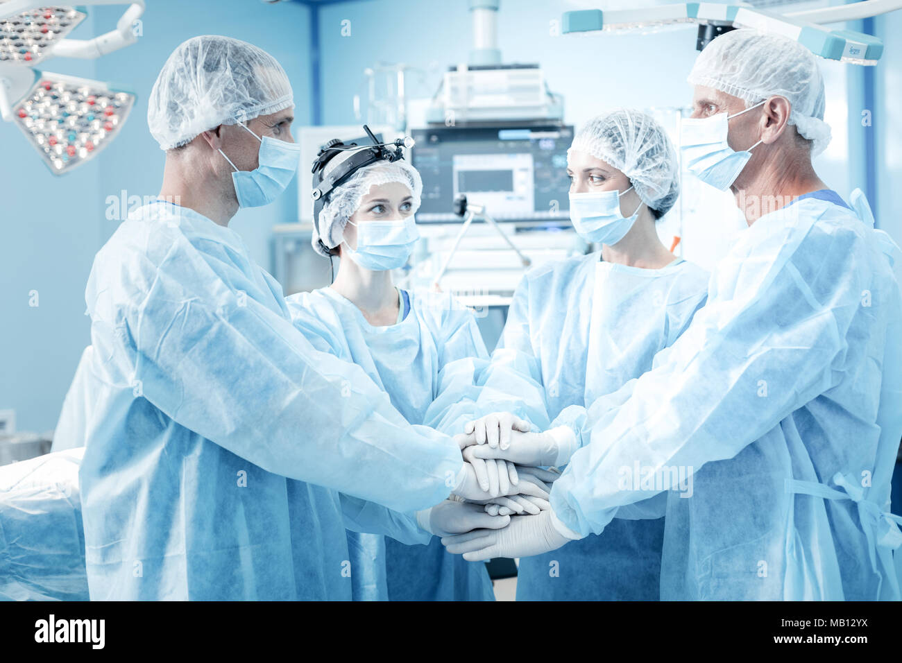 Positive nice surgeons holding hands together Stock Photo - Alamy