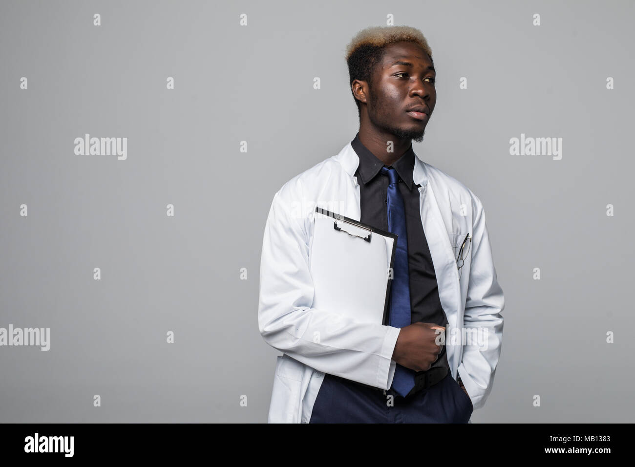 Friendly Afro-American doctor holding a clipboard and smiling at the ...