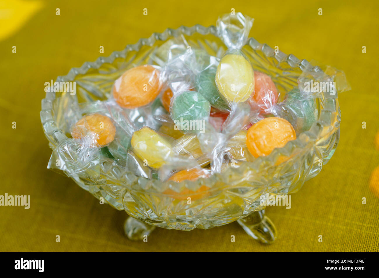 candys in glass bowl on table with yellow sheet Stock Photo - Alamy