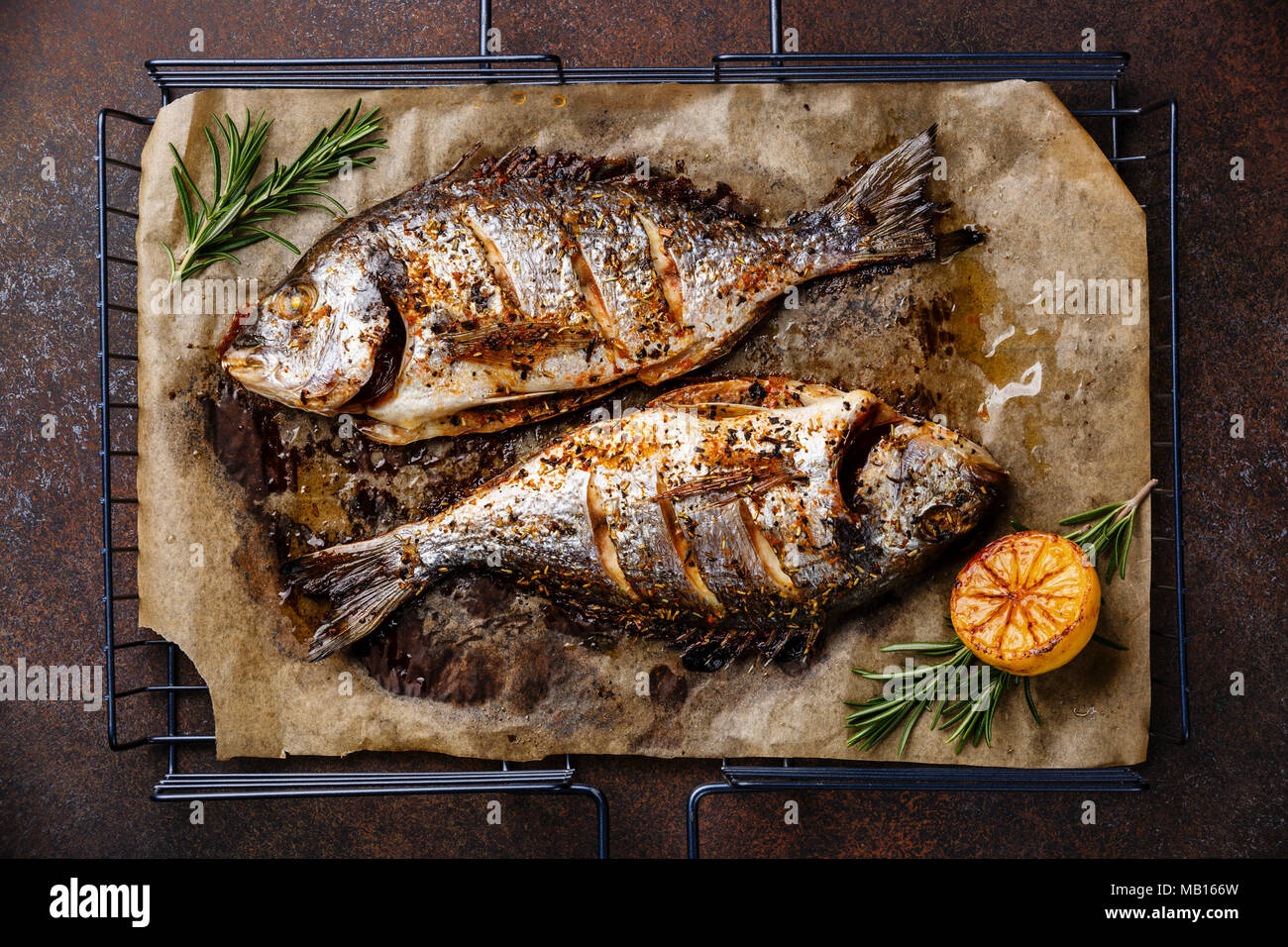 Grilled Fish Dorado on metal grill grid with lemon and rosemary on dark ...