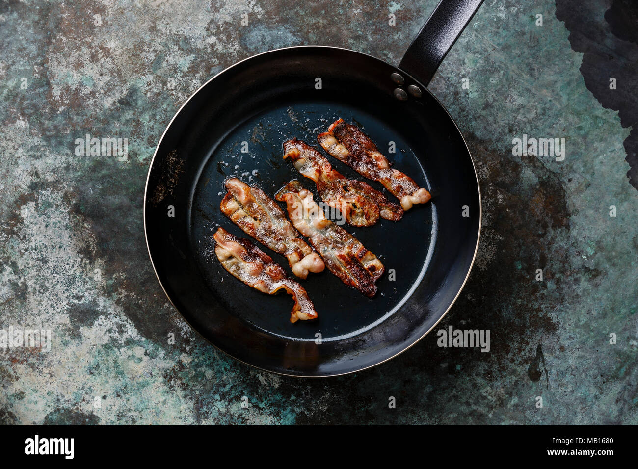 Fried bacon in frying cooking pan on metal background Stock Photo - Alamy