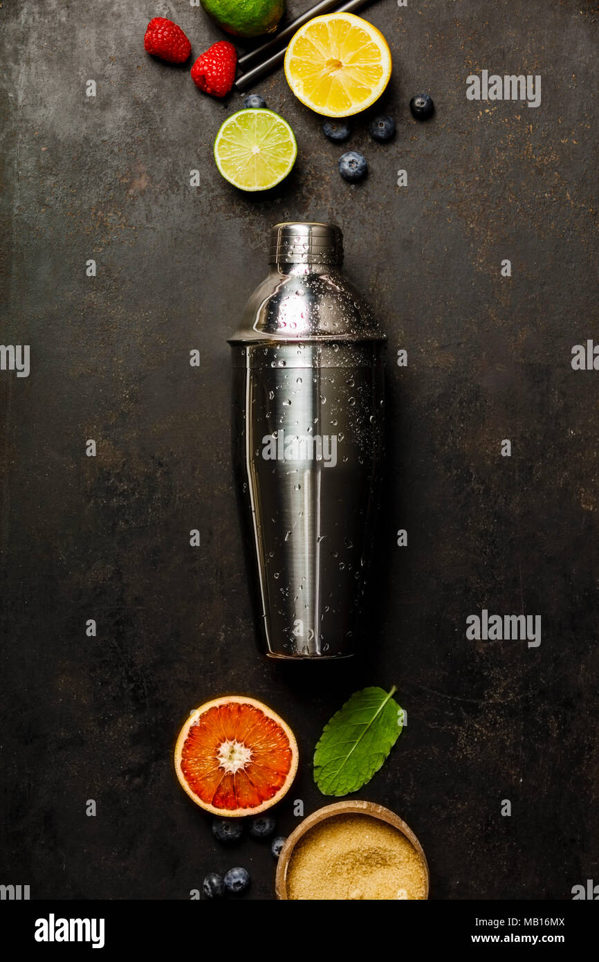 Cocktail shaker, tropical fruits and leaves on a dark background. Top ...