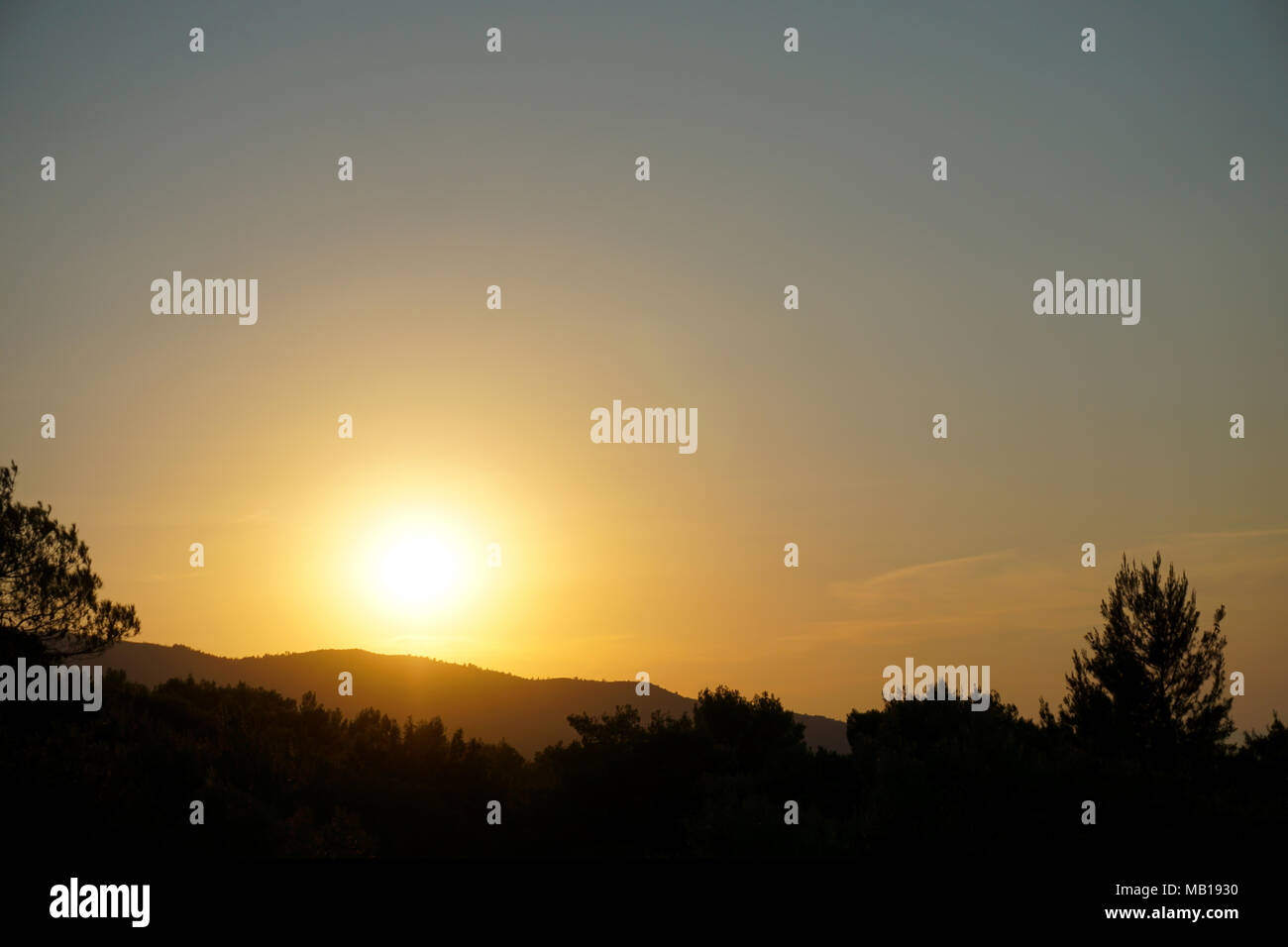 Sunset at the sea. Sun falling down behind mountain Stock Photo - Alamy
