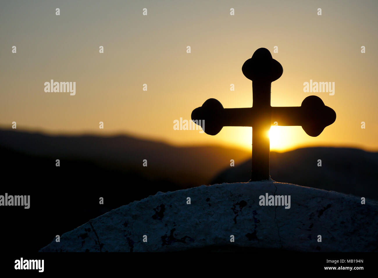 Isolated cross on sunset with sun in background Stock Photo - Alamy