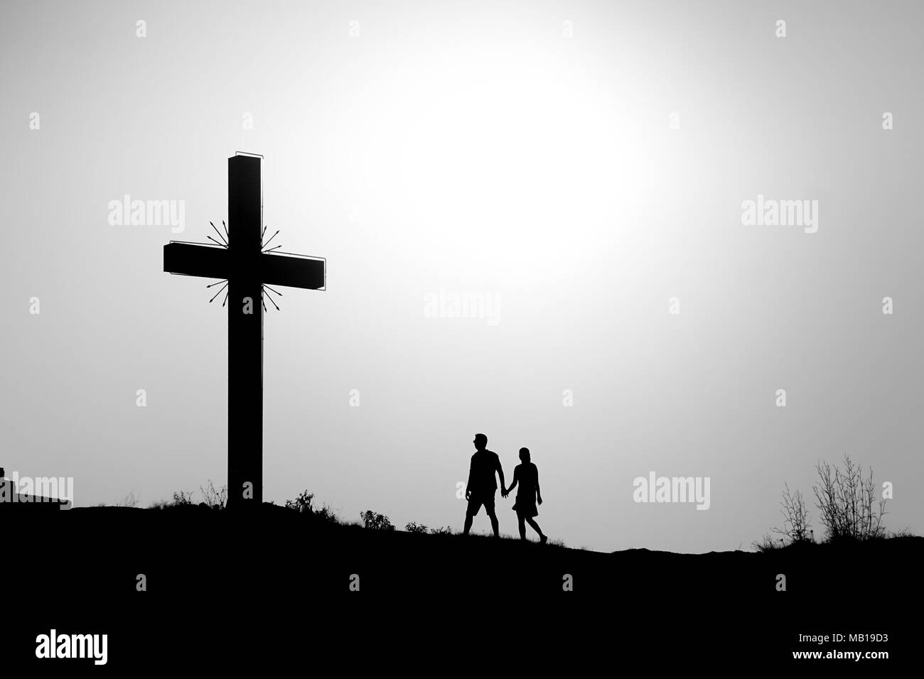 Silhouette of cross on sunset with man and woman holding hands and ...