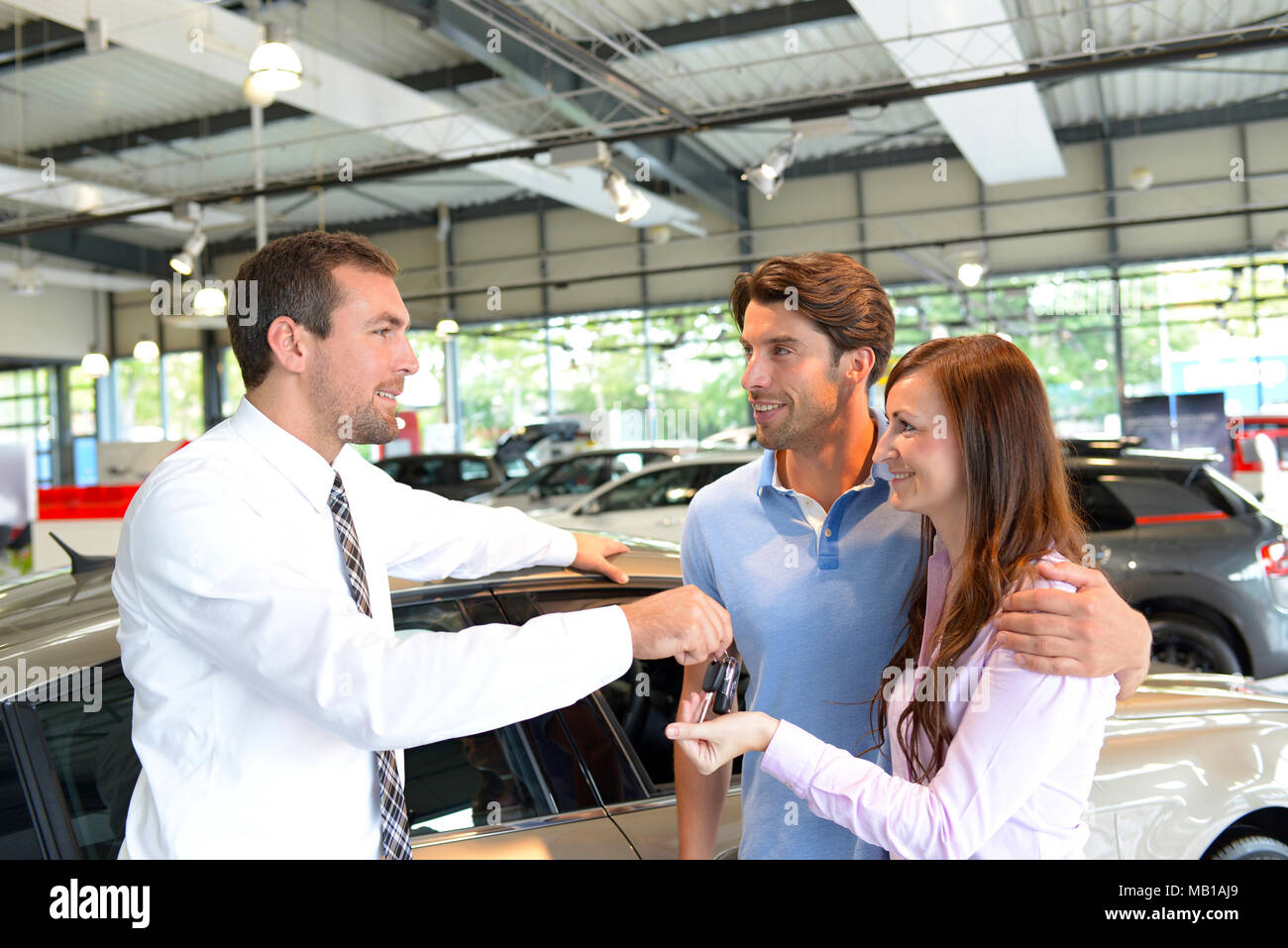 car salesman hands over the car key in the car dealership to customers ...