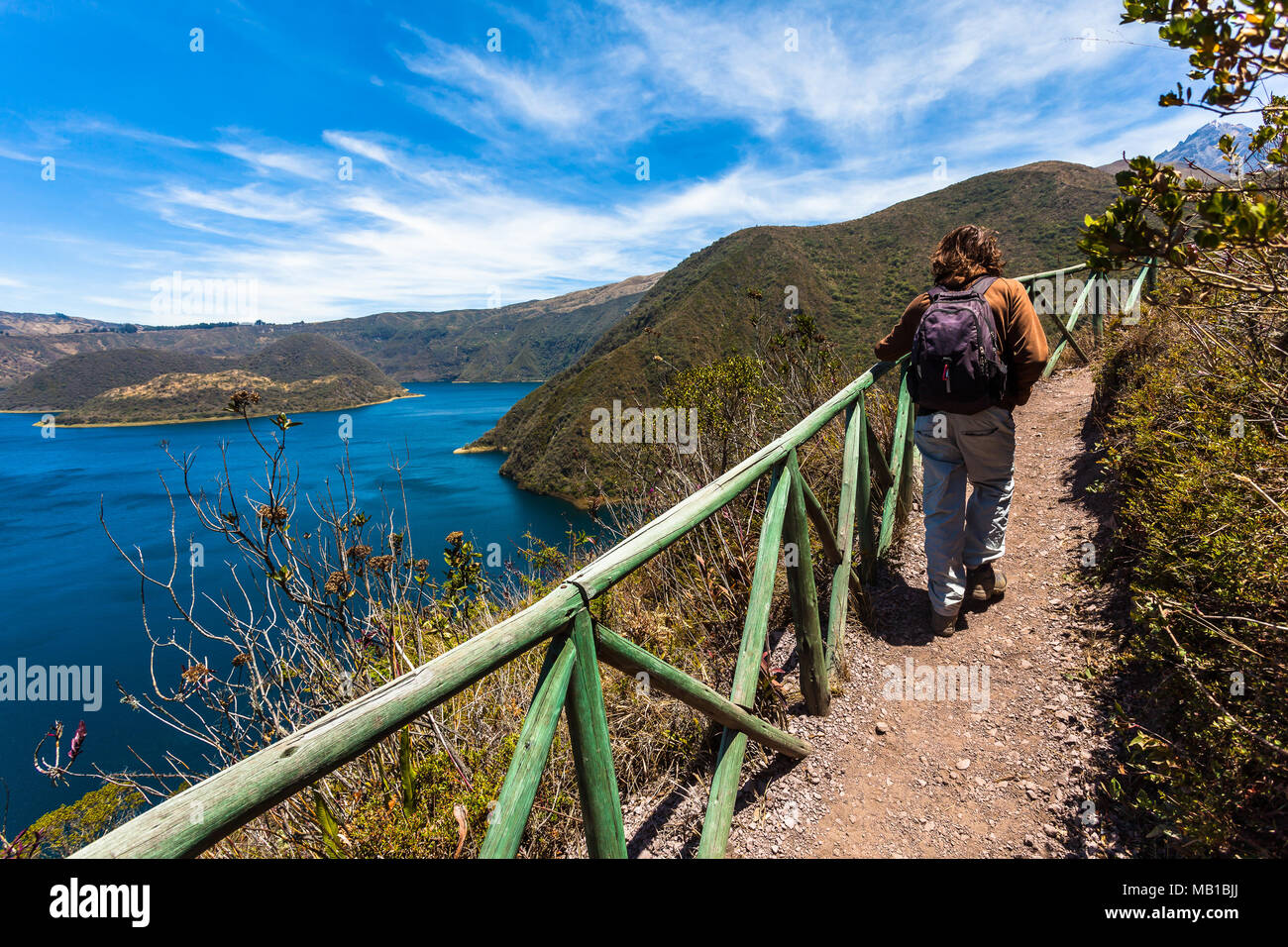 A mountaineer walks the trail to the edge of the Cuicocha lagoon inside ...