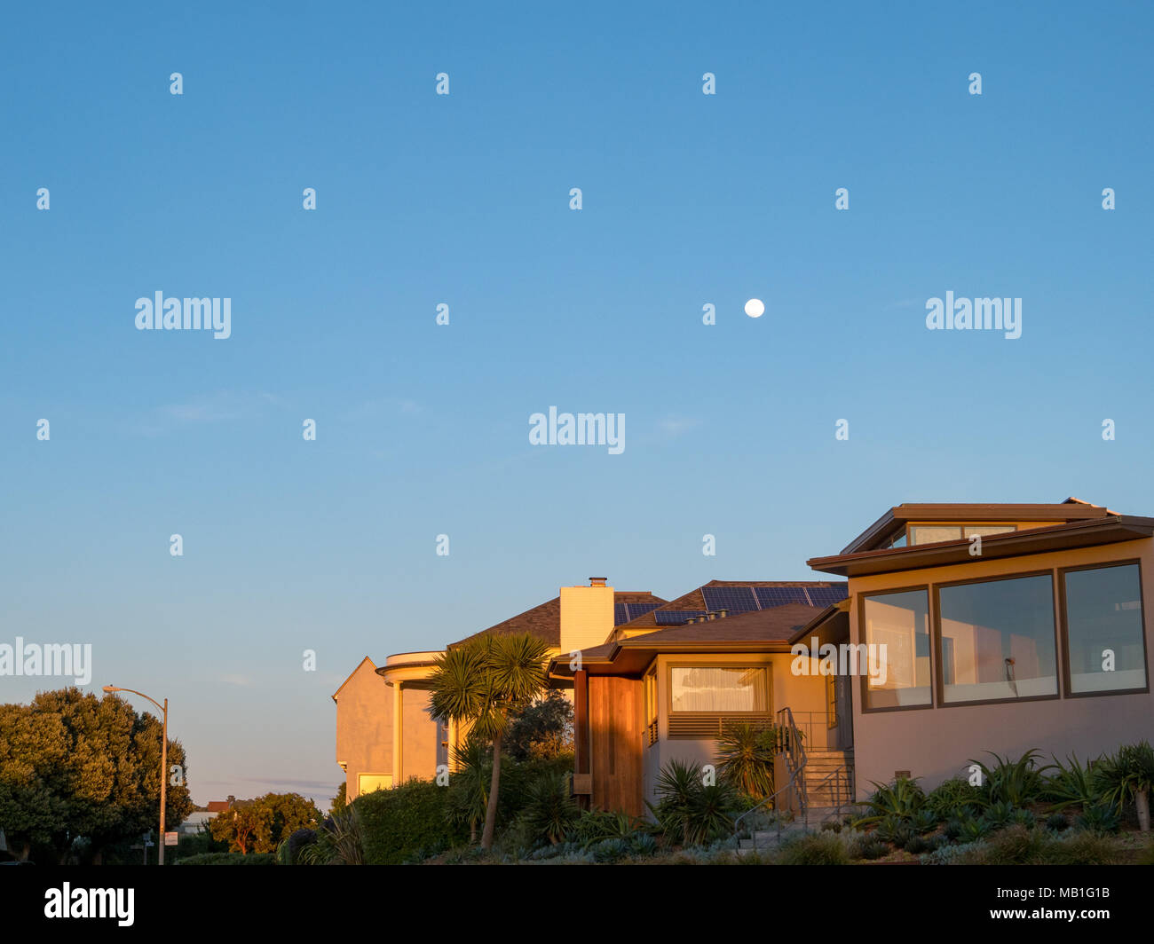 Full moon seen while setting sun in neighborhood near house Stock Photo ...