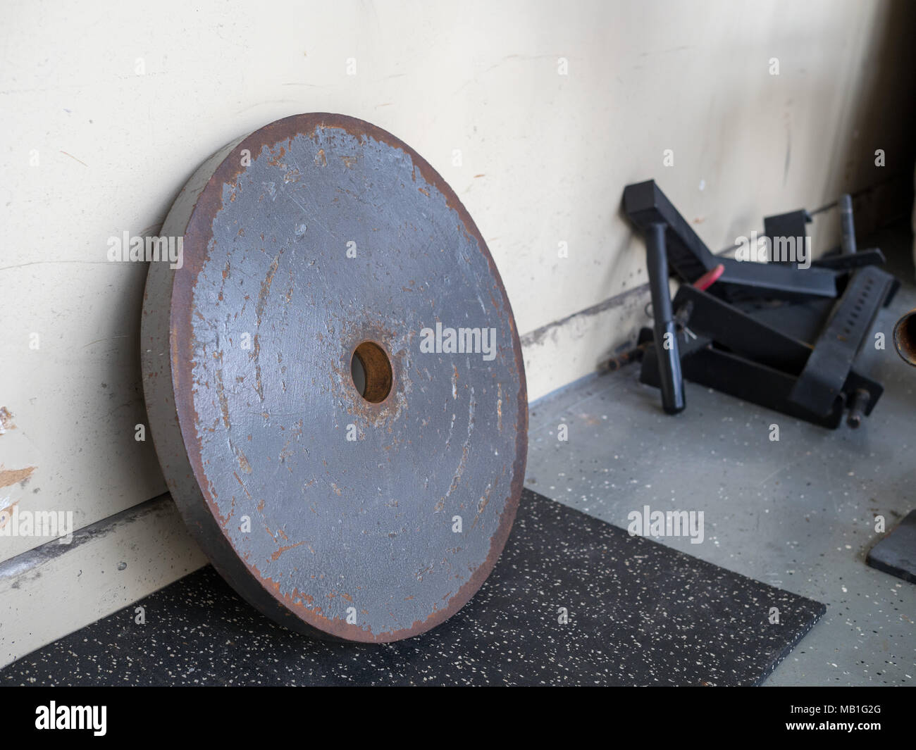 Rusty 45 lb weight sitting on gym floor ready to use Stock Photo - Alamy