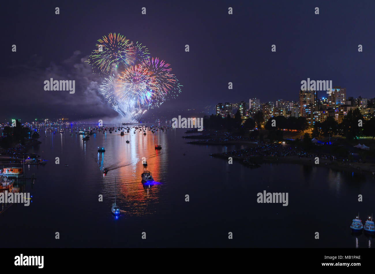 Multicolored fireworks lights over a bridge on the ocean in a big city ...