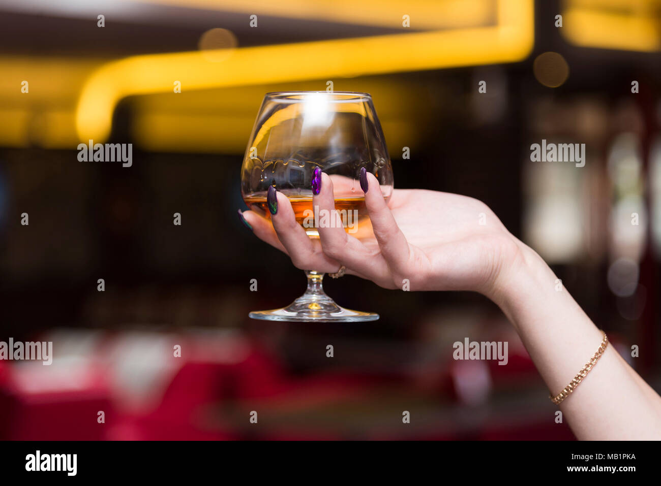 Female hand holding a glass of cognac, blurred background Stock Photo ...
