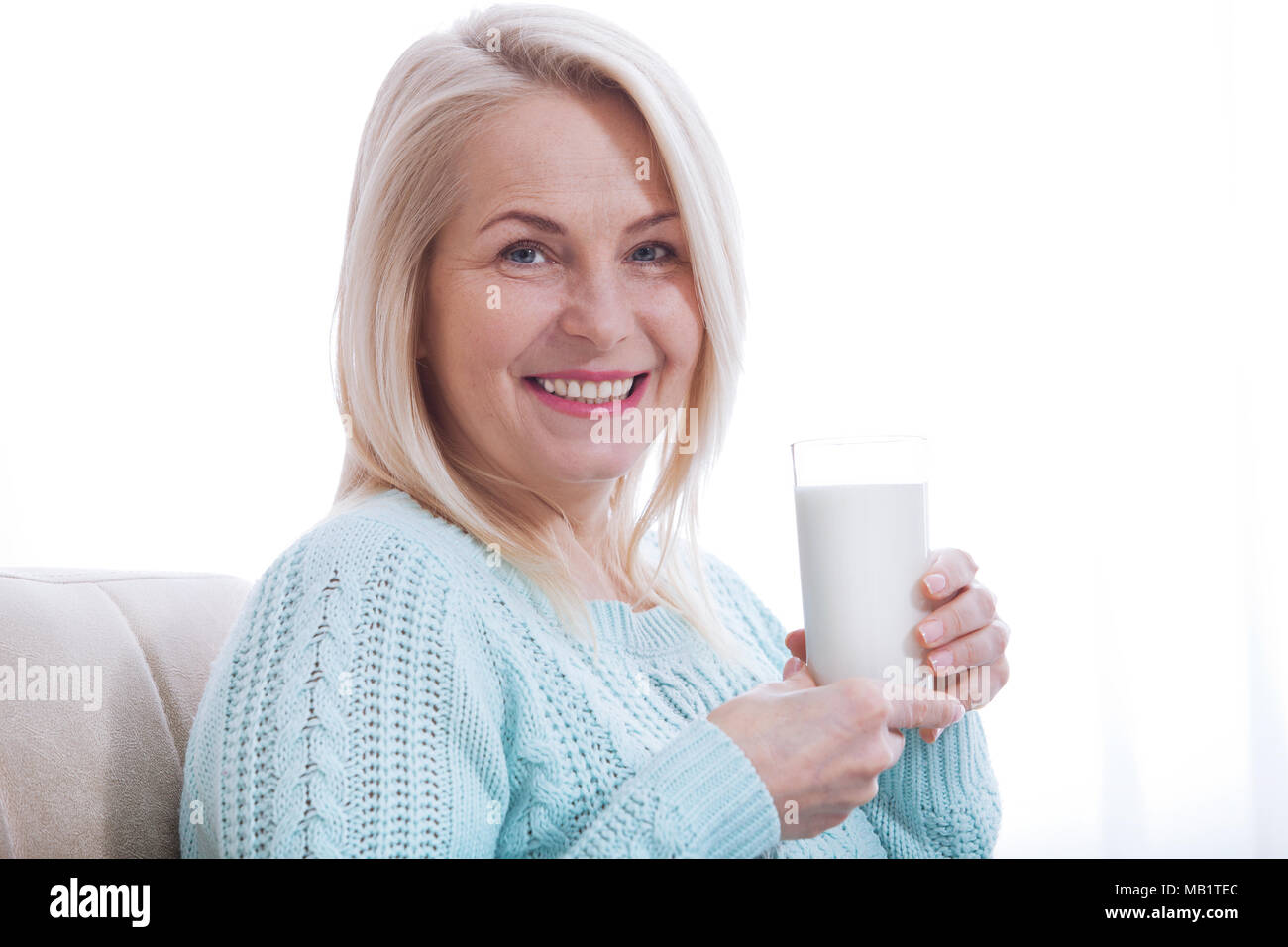 Happy middle aged woman drinking milk Stock Photo - Alamy