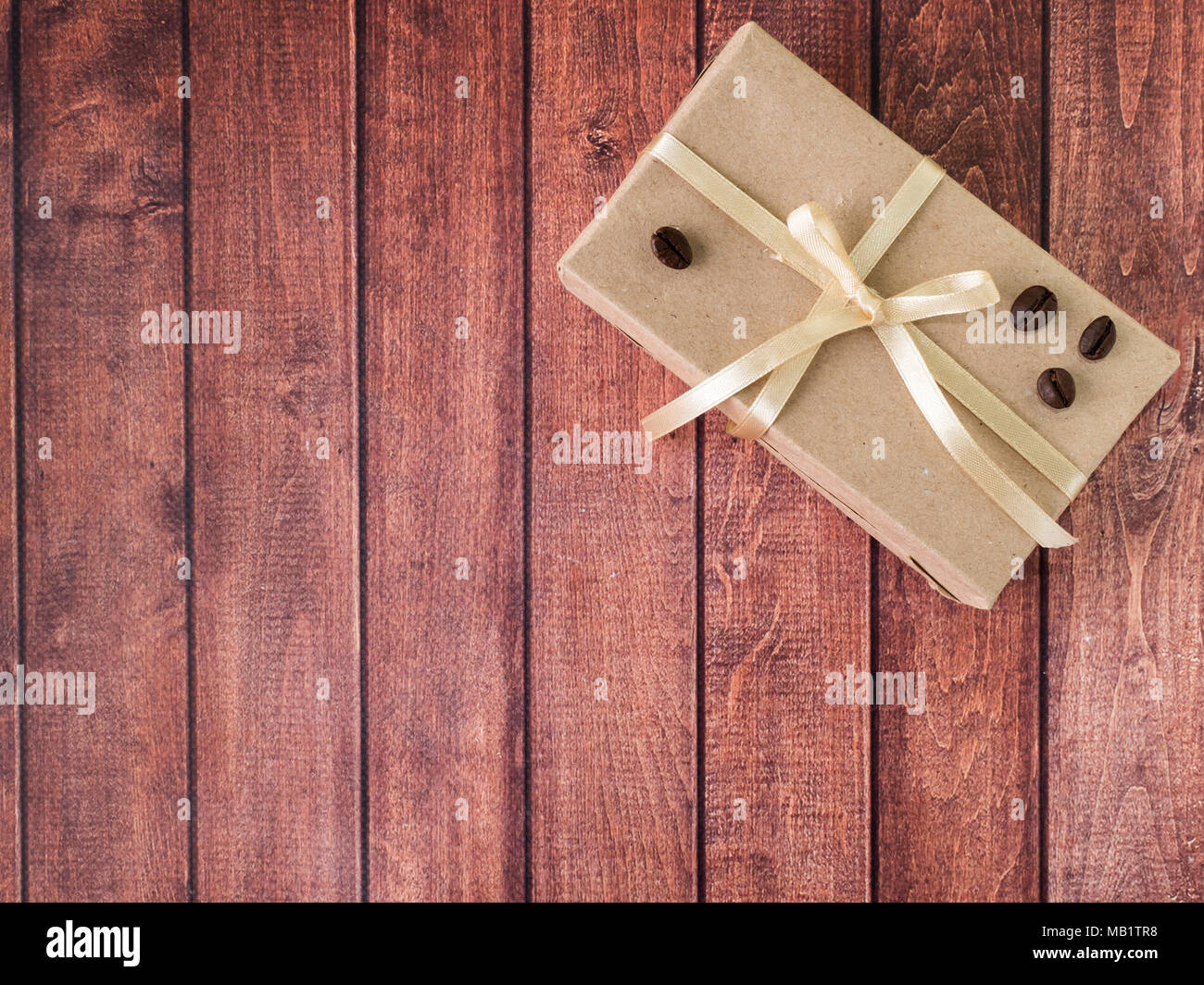 Beige gift box with ribbon and bow on wooden background, place for ...