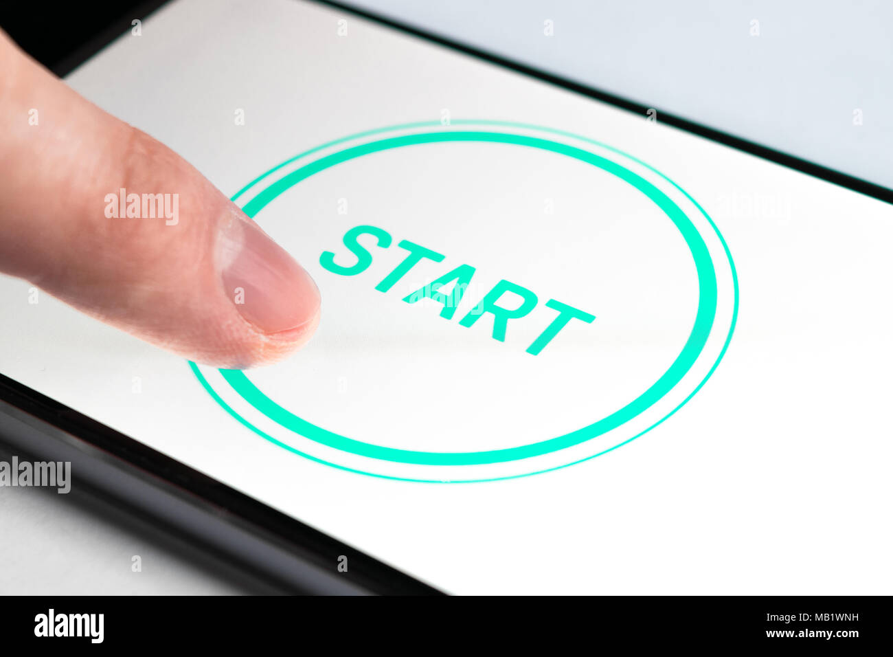A finger presses the start button on the screen of a smarphone Stock ...