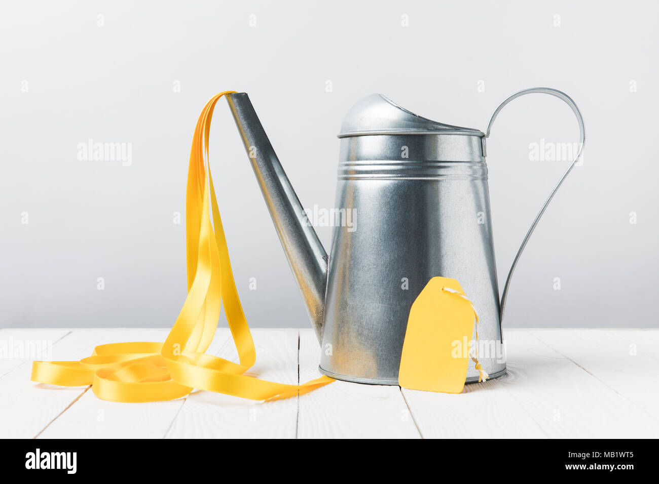 close-up view of shiny watering can with yellow ribbon and blank label ...
