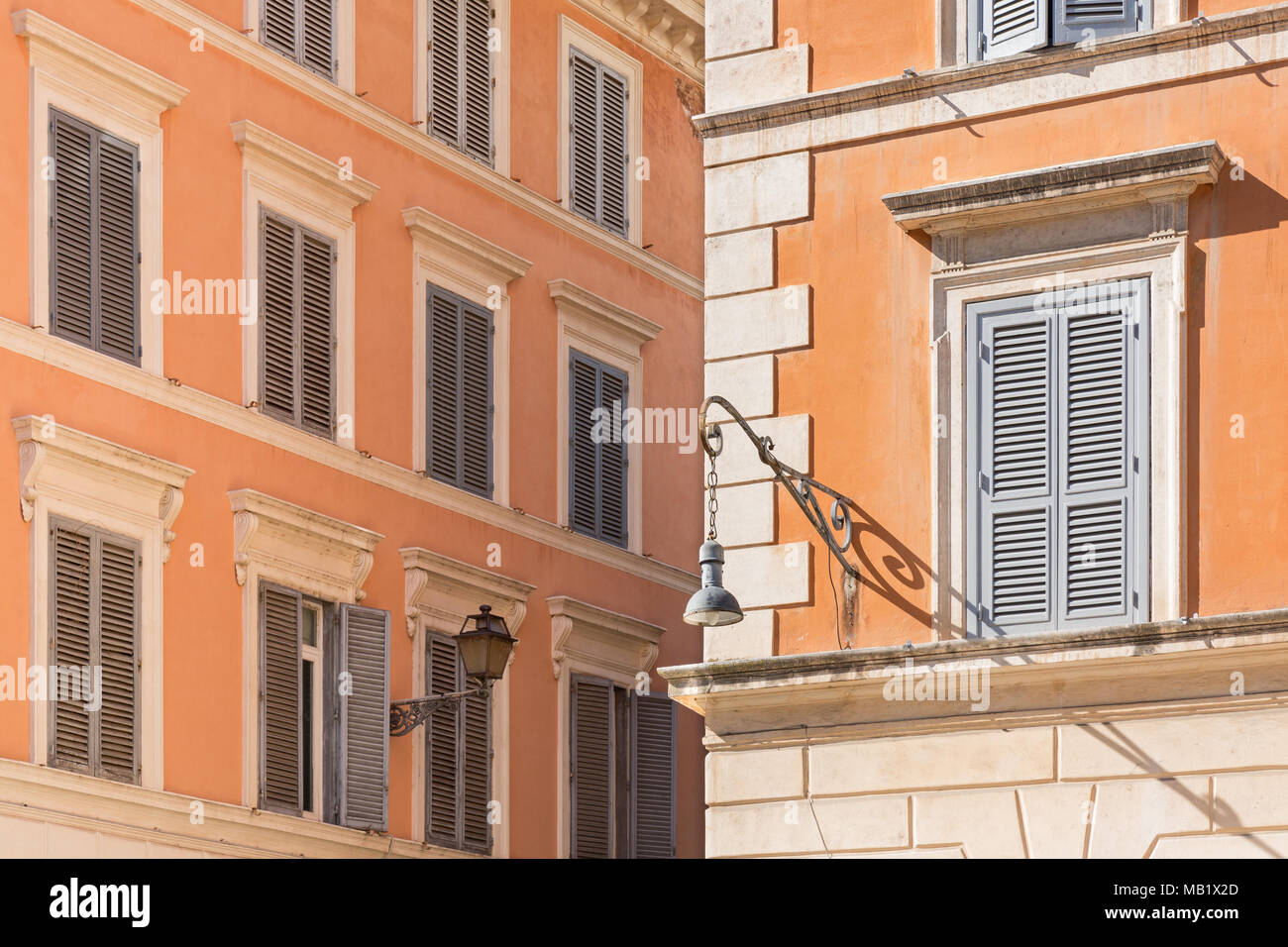 Two styles of lamps on buildings above a street corner in Rome, Italy ...