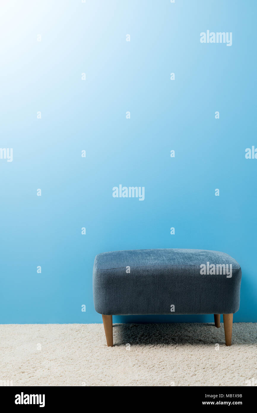 soft hassock standing on carpet in front of blue wall Stock Photo - Alamy