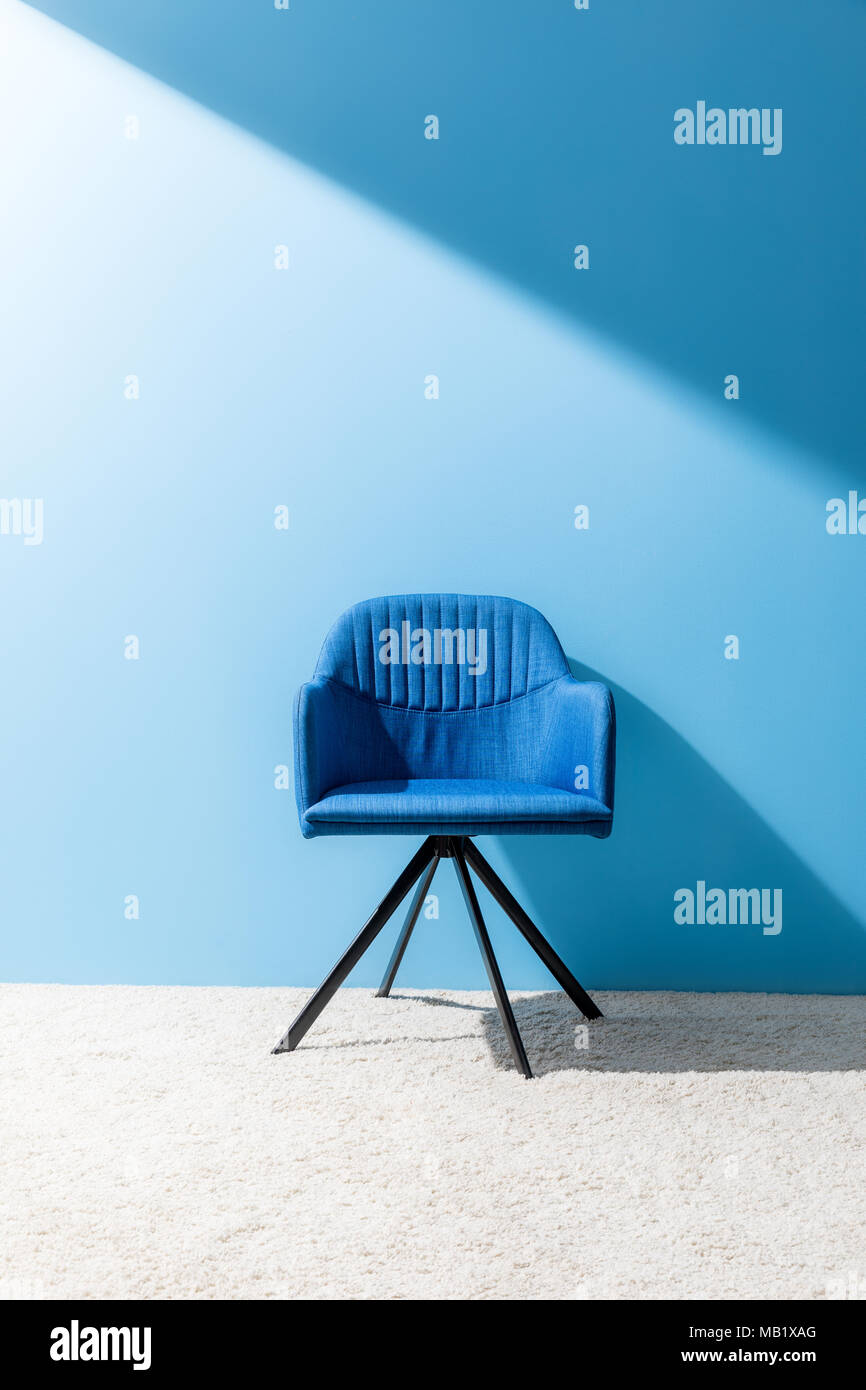 comfy blue chair in front of blue wall Stock Photo - Alamy
