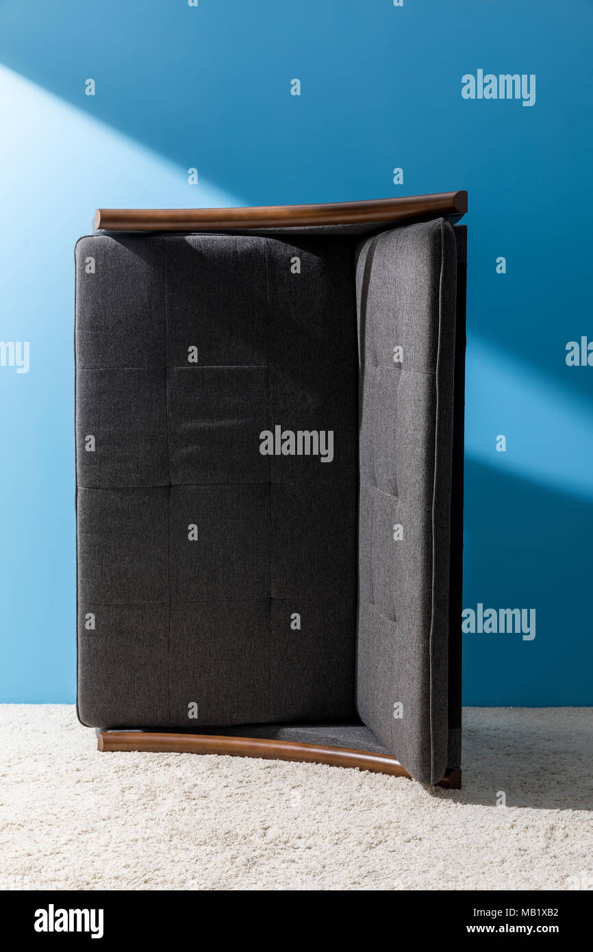 couch flipped on side in front of blue wall Stock Photo - Alamy