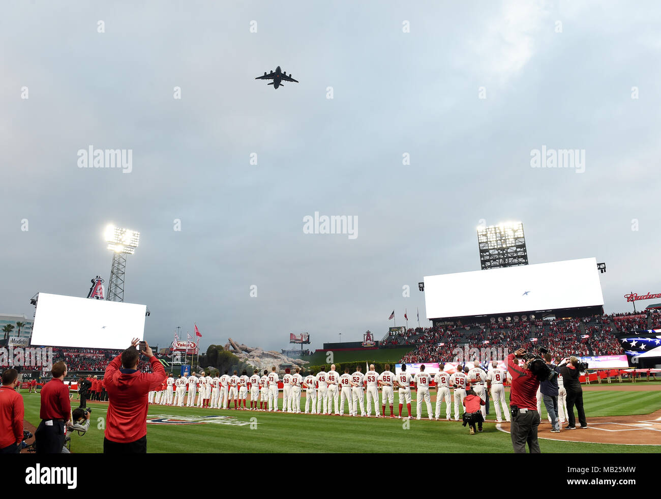A Boeing C-17 Globemaster III flies over as Los Angeles Angels players ...